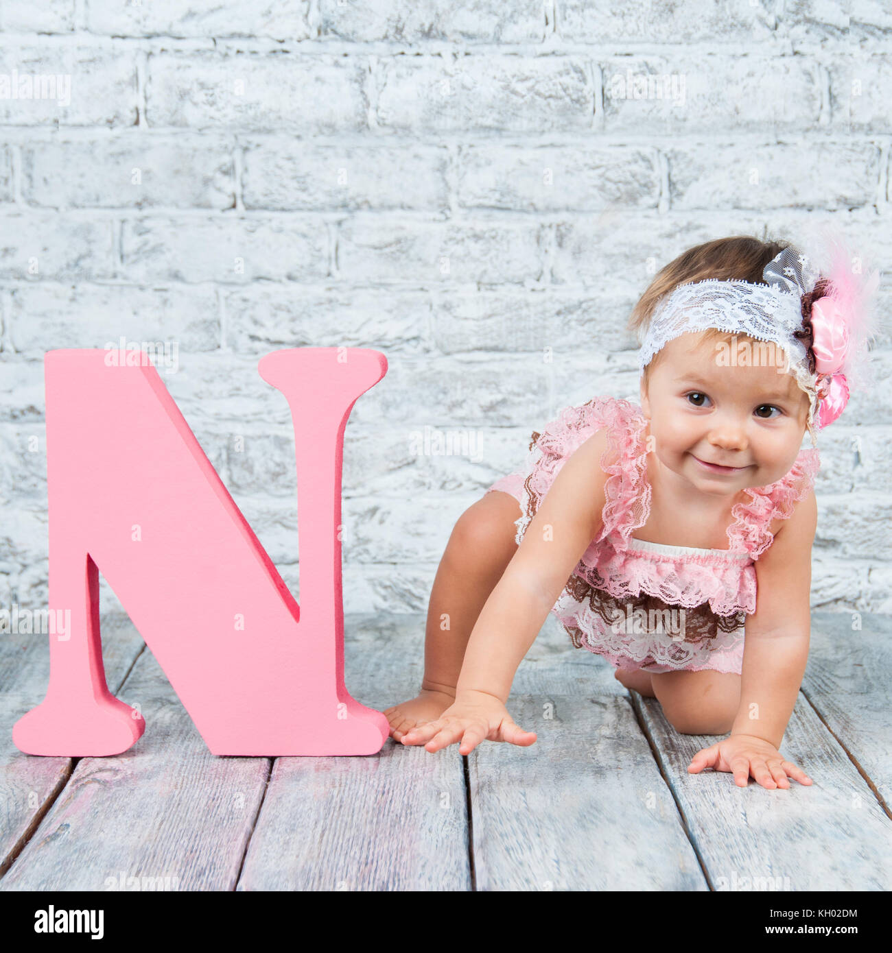 Beautiful and cute girl in pink dress with the letter N. Emotional girl ...