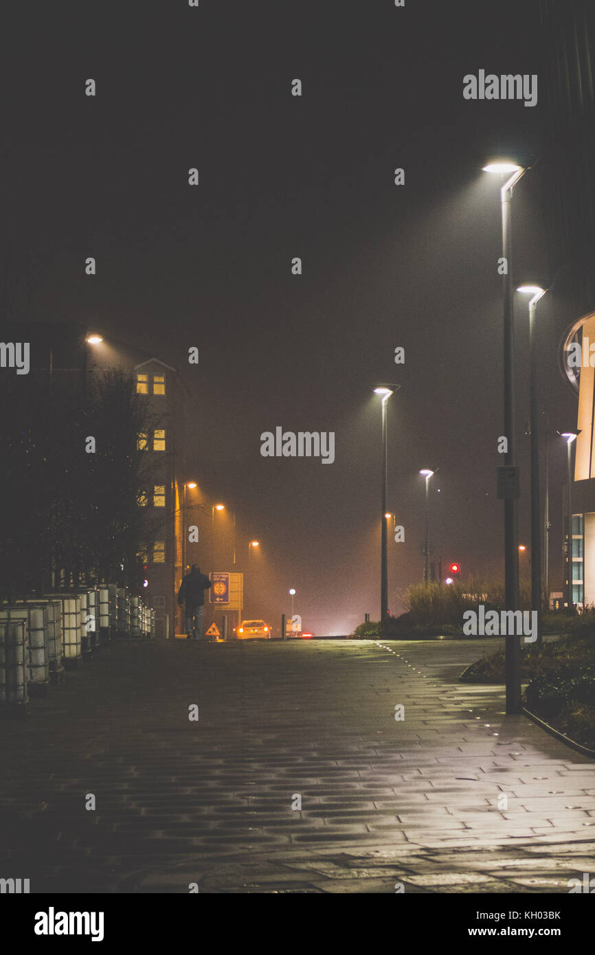 moody and dark road with fog and mist shining through street lights ...