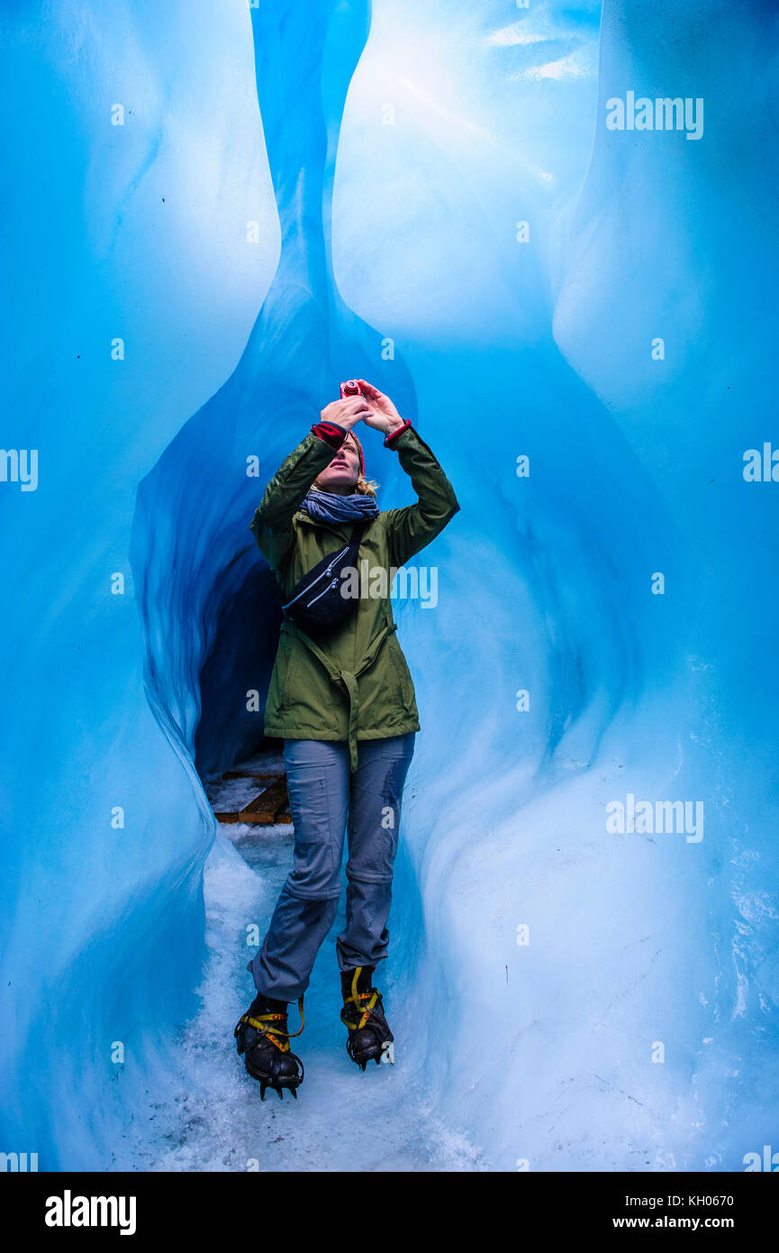 Woman photographing in a ice cave in Fox Glacier, South Island, New ...