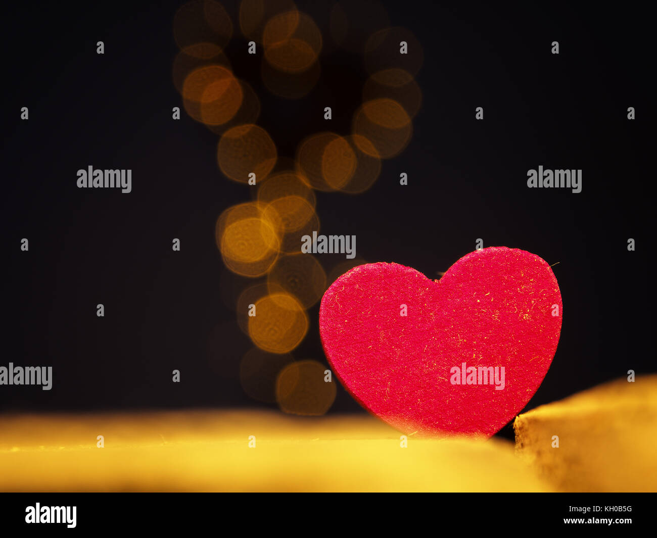 Close up of a red wooden heart shape with blurred heart shaped lights ...