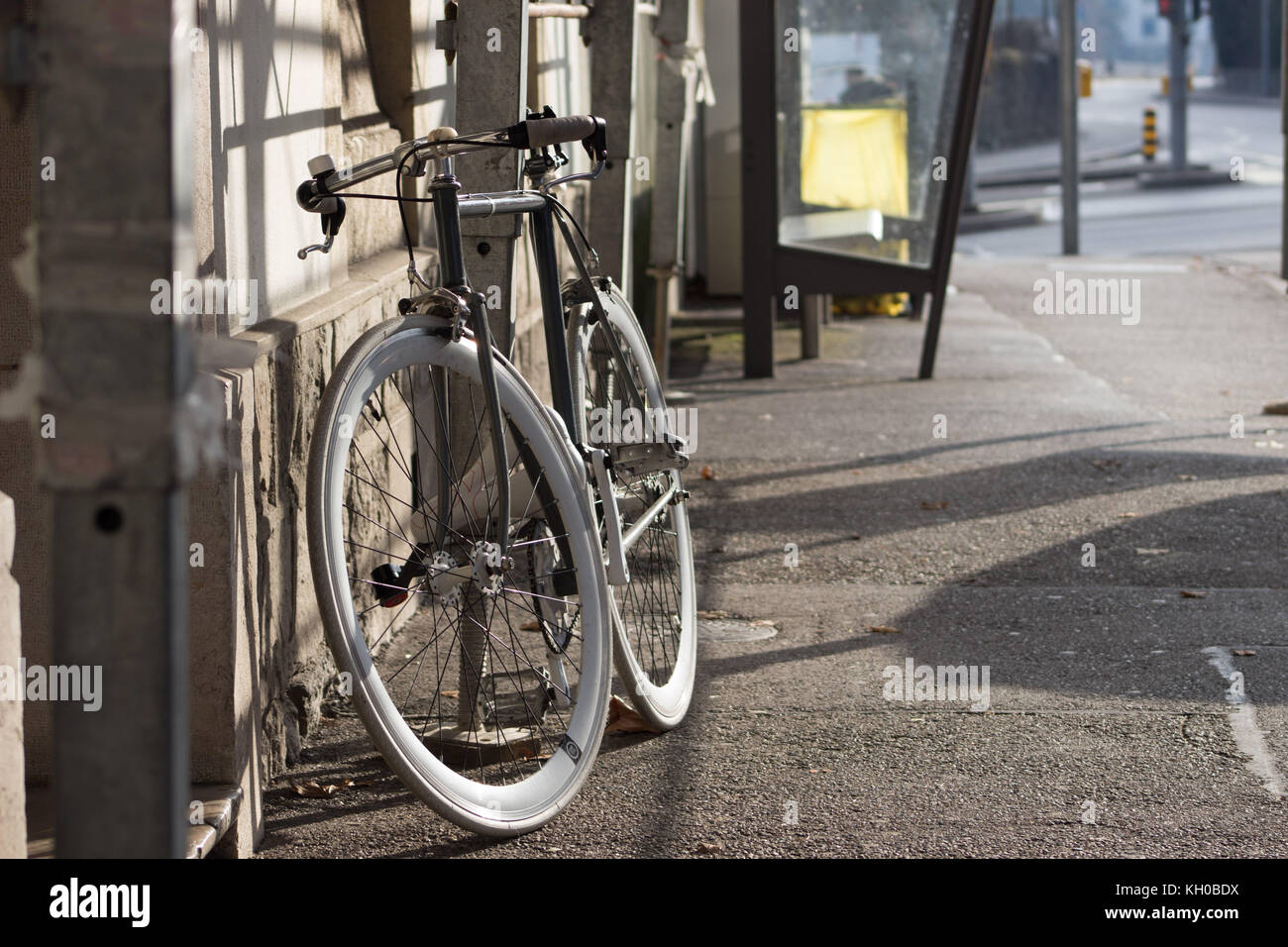 bicycle locked up against a wall in the sun Stock Photo - Alamy
