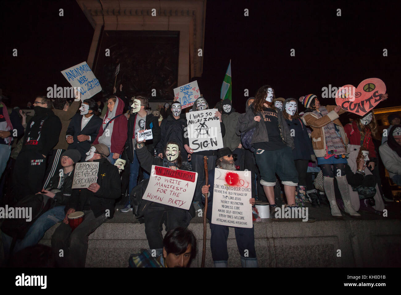 Protesters wear Guy Fawkes masks and hold up homemade signs and ...