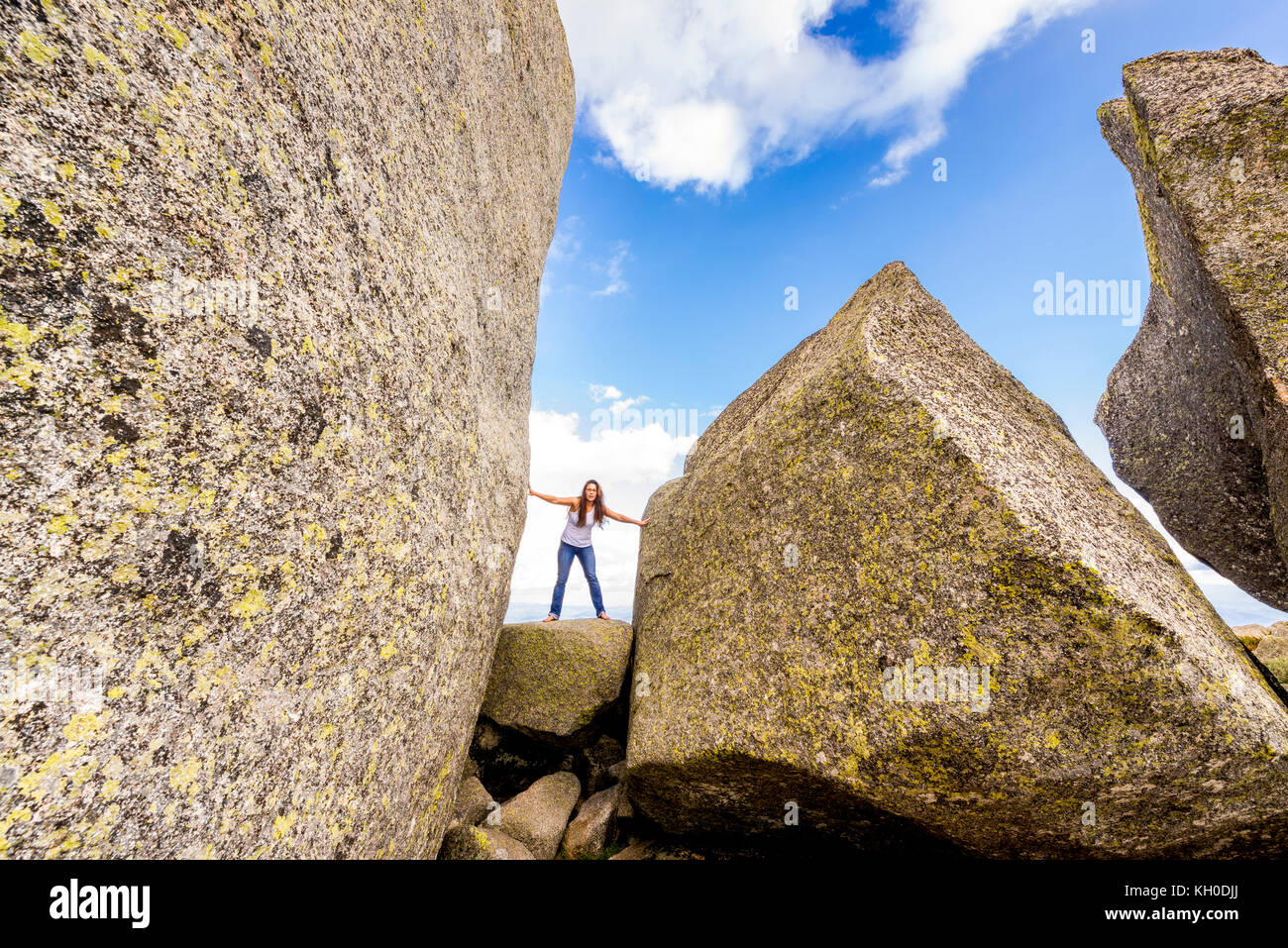 A woman stretches her arms and legs in between the massive granite ...