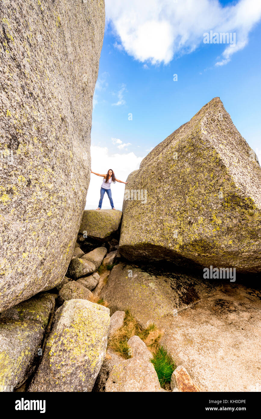 A woman stretches her arms and legs in between the massive granite ...