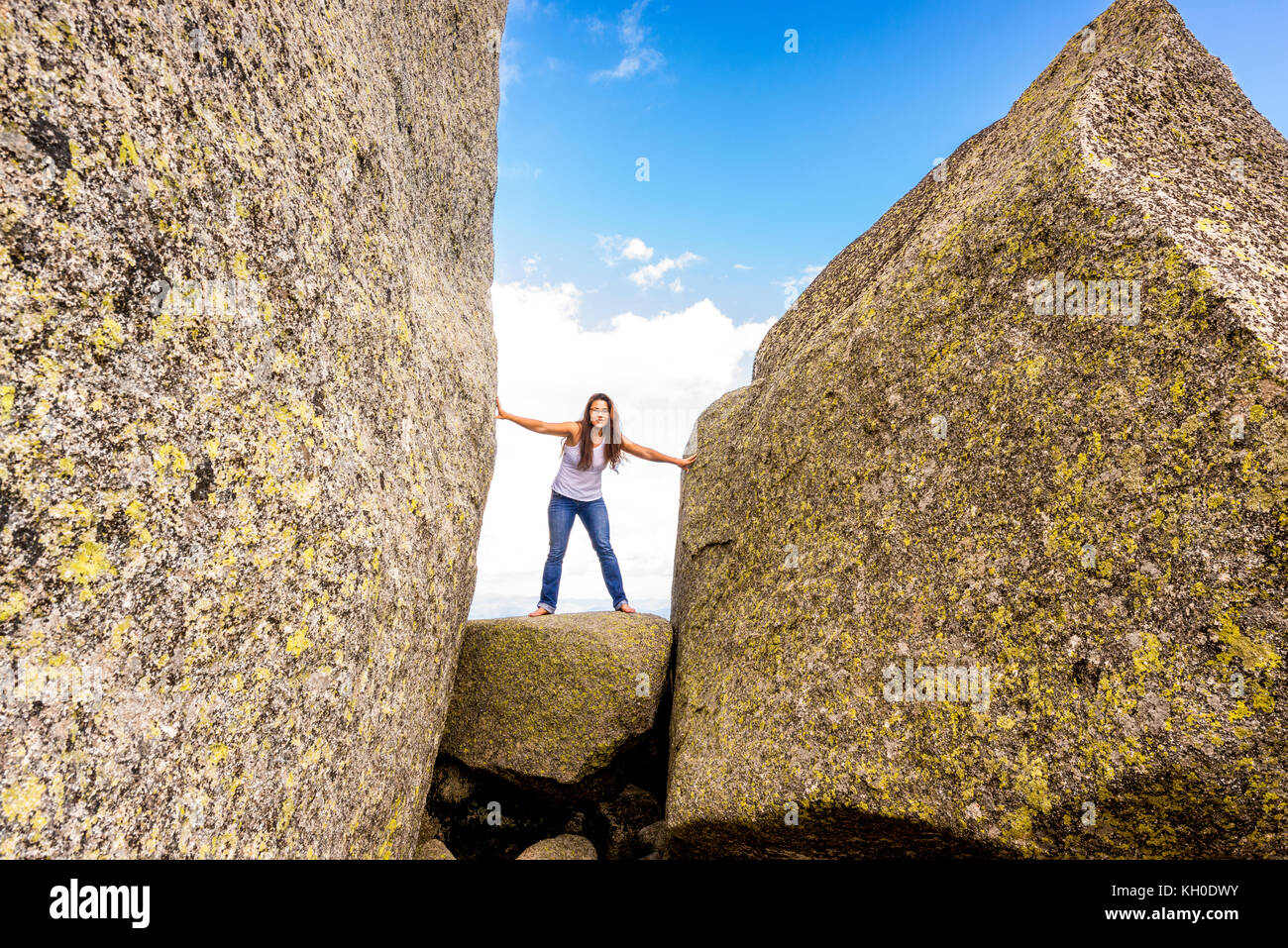 A woman stretches her arms and legs in between the massive granite ...