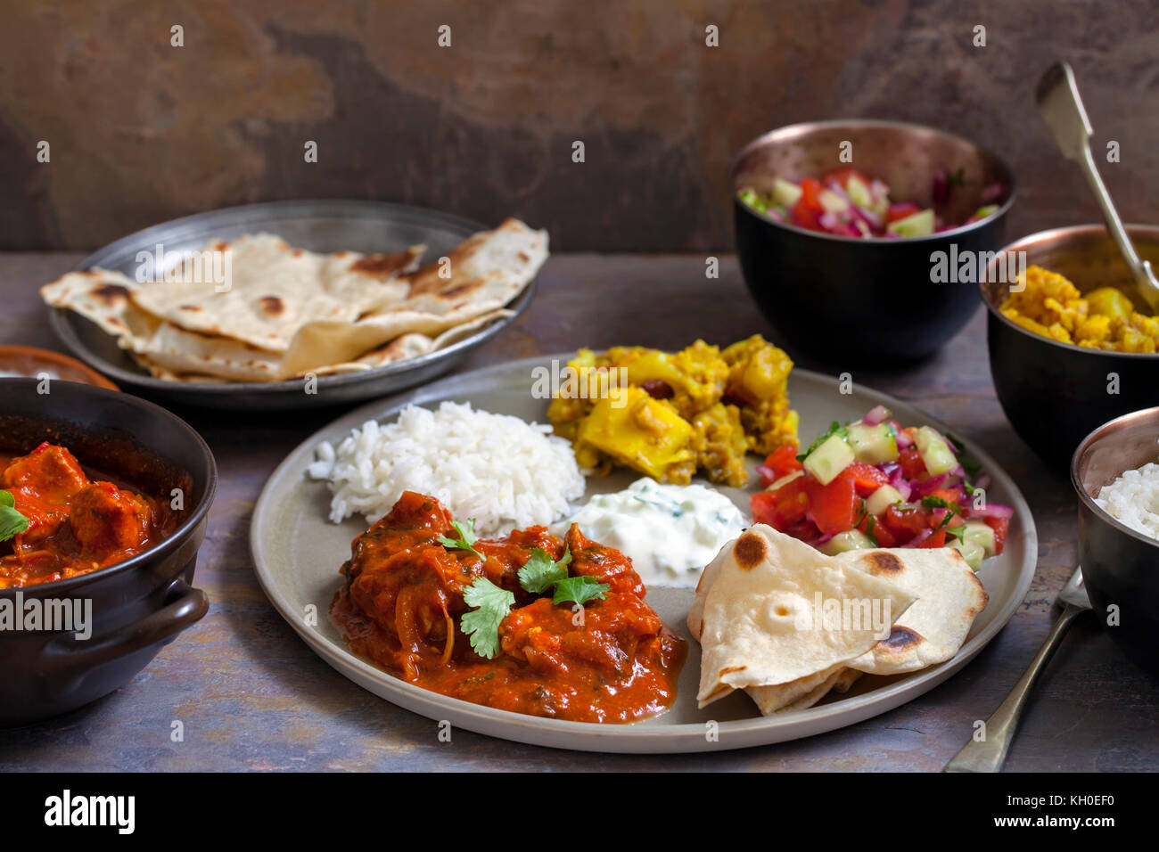 Indian meal with chicken tikka masala, aloo gobi, salad, rice and flat ...