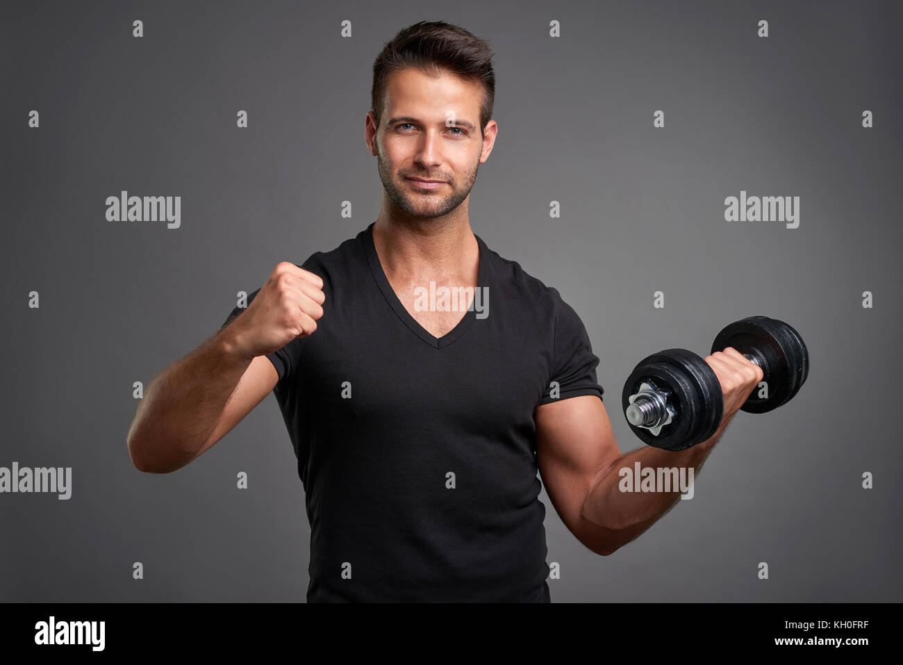 A handsome young man lifting weight smiling and raising his fist Stock ...