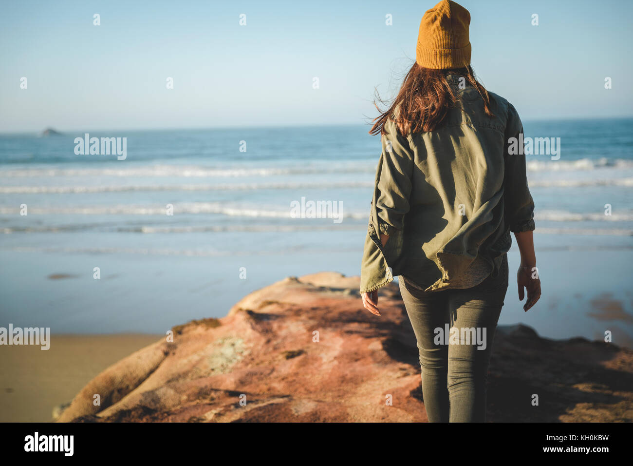 Woman with a yellow cap and walking over the cliff to see the beach ...