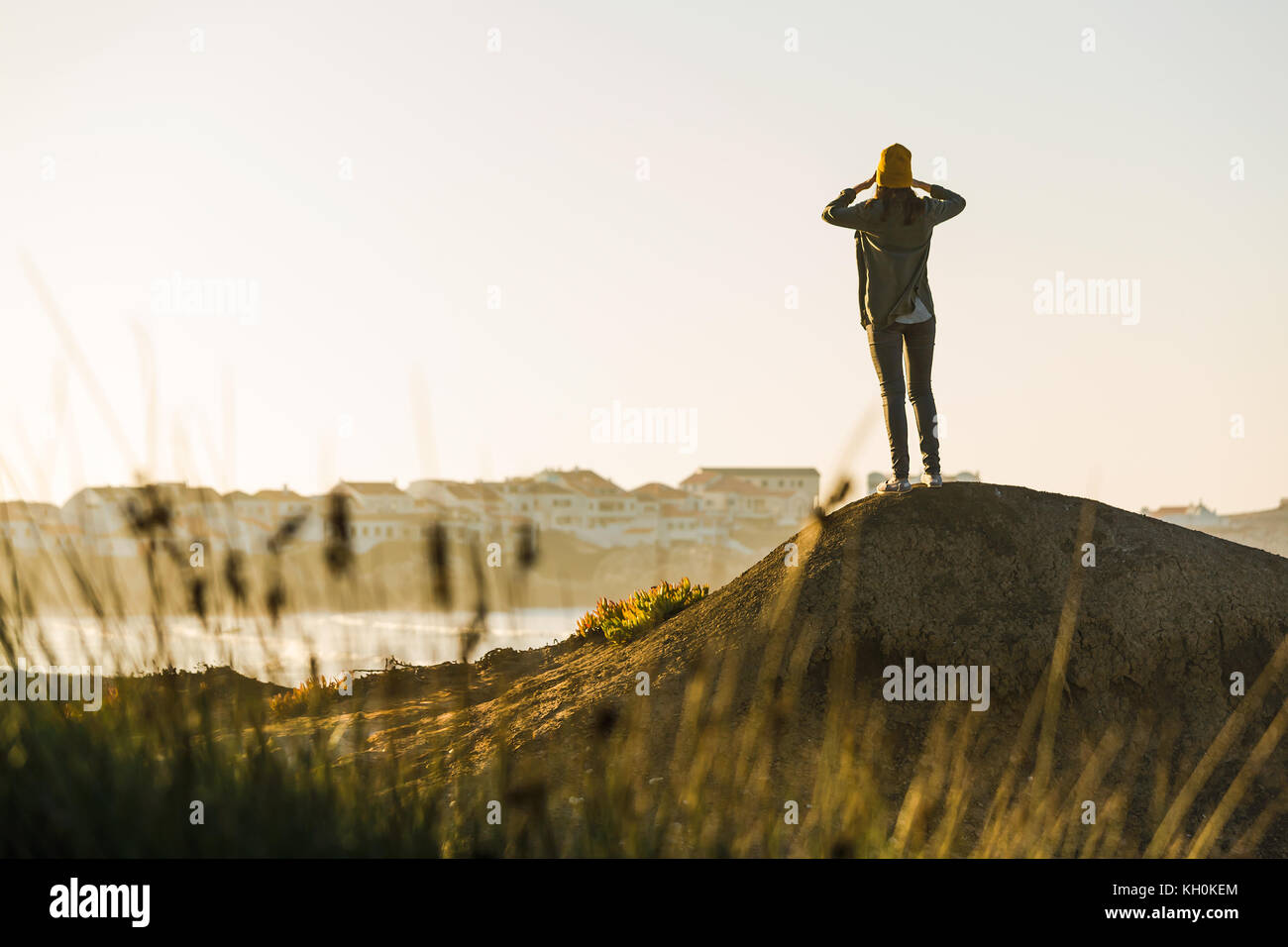 Woman with yellow cap over the cliff seeing the beach Stock Photo - Alamy