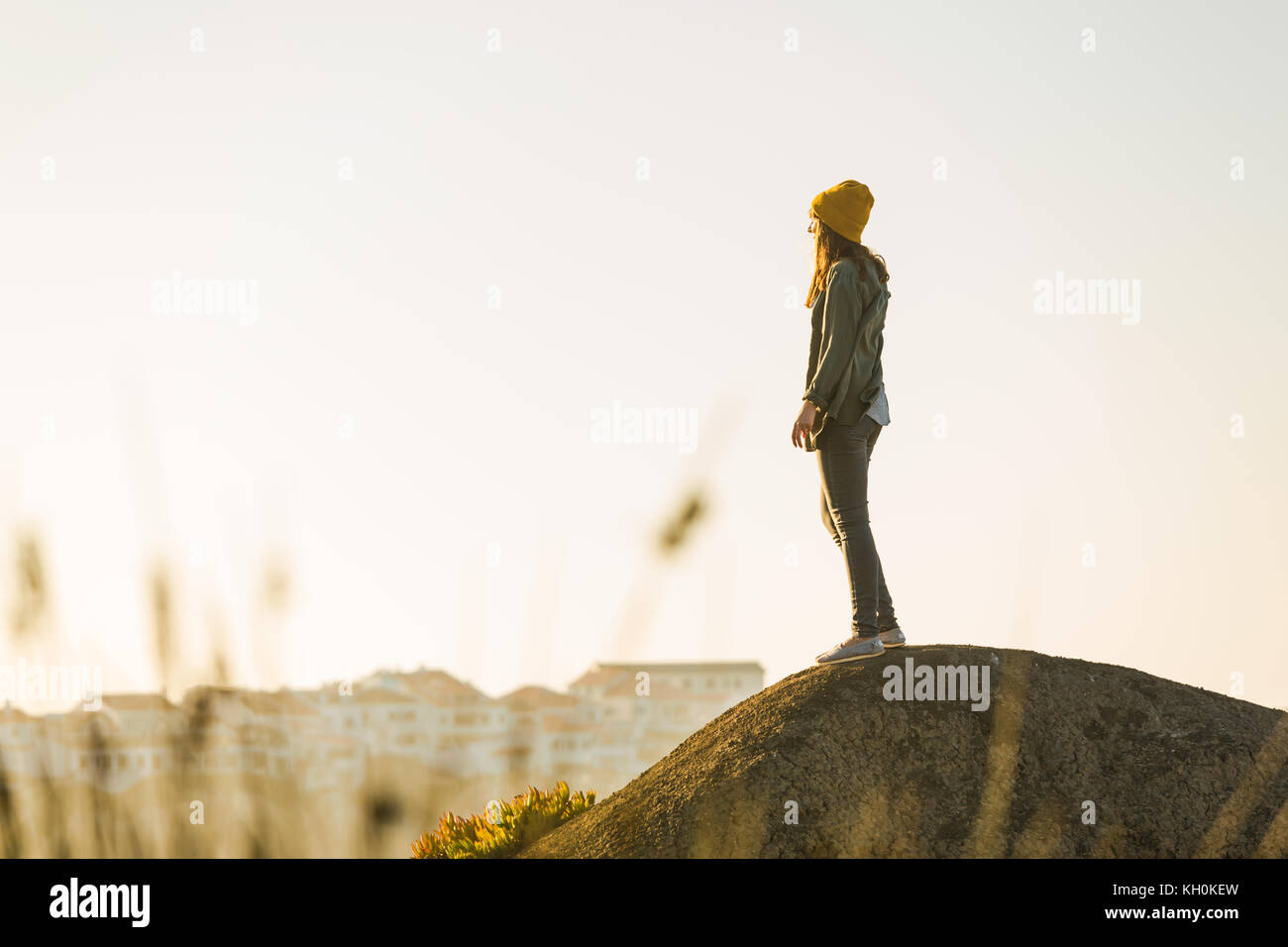 Woman with yellow cap over the cliff seeing the beach Stock Photo - Alamy