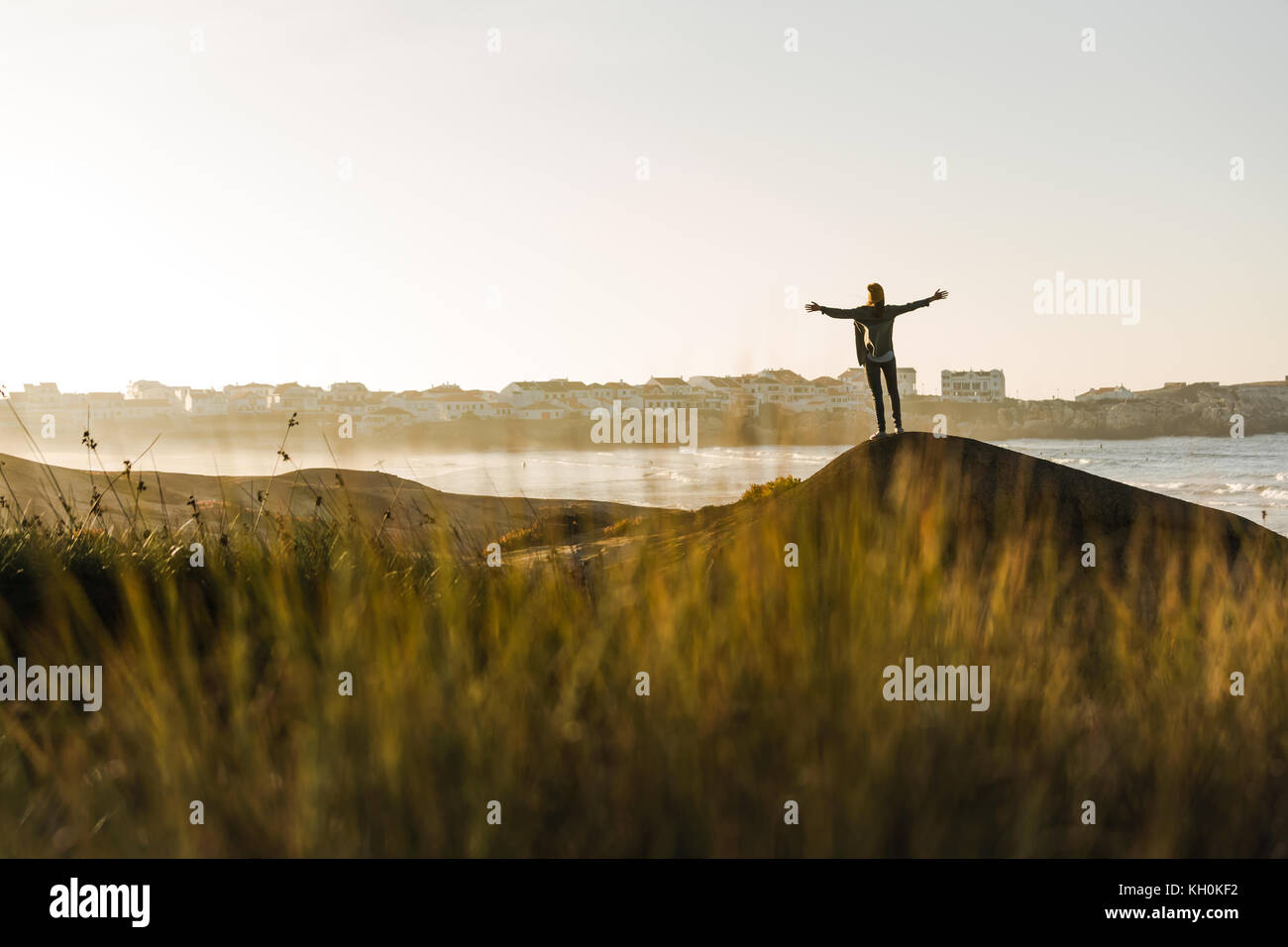 Happy woman with arms raised over the cliff seeing the beach Stock ...