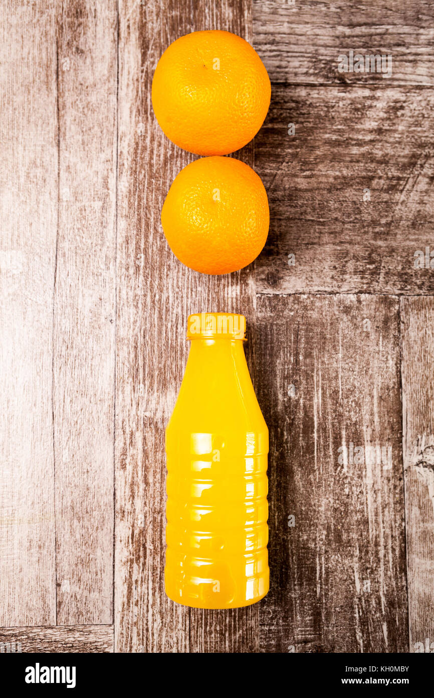 Orange juice in plastic bottle next to two oranges Stock Photo - Alamy