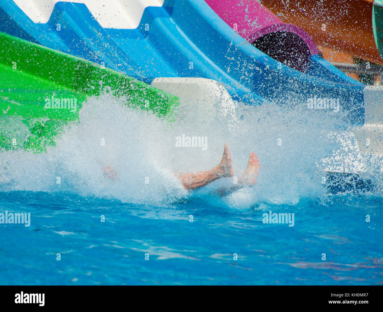 Person entering water from aqua park slide creating large splash ...
