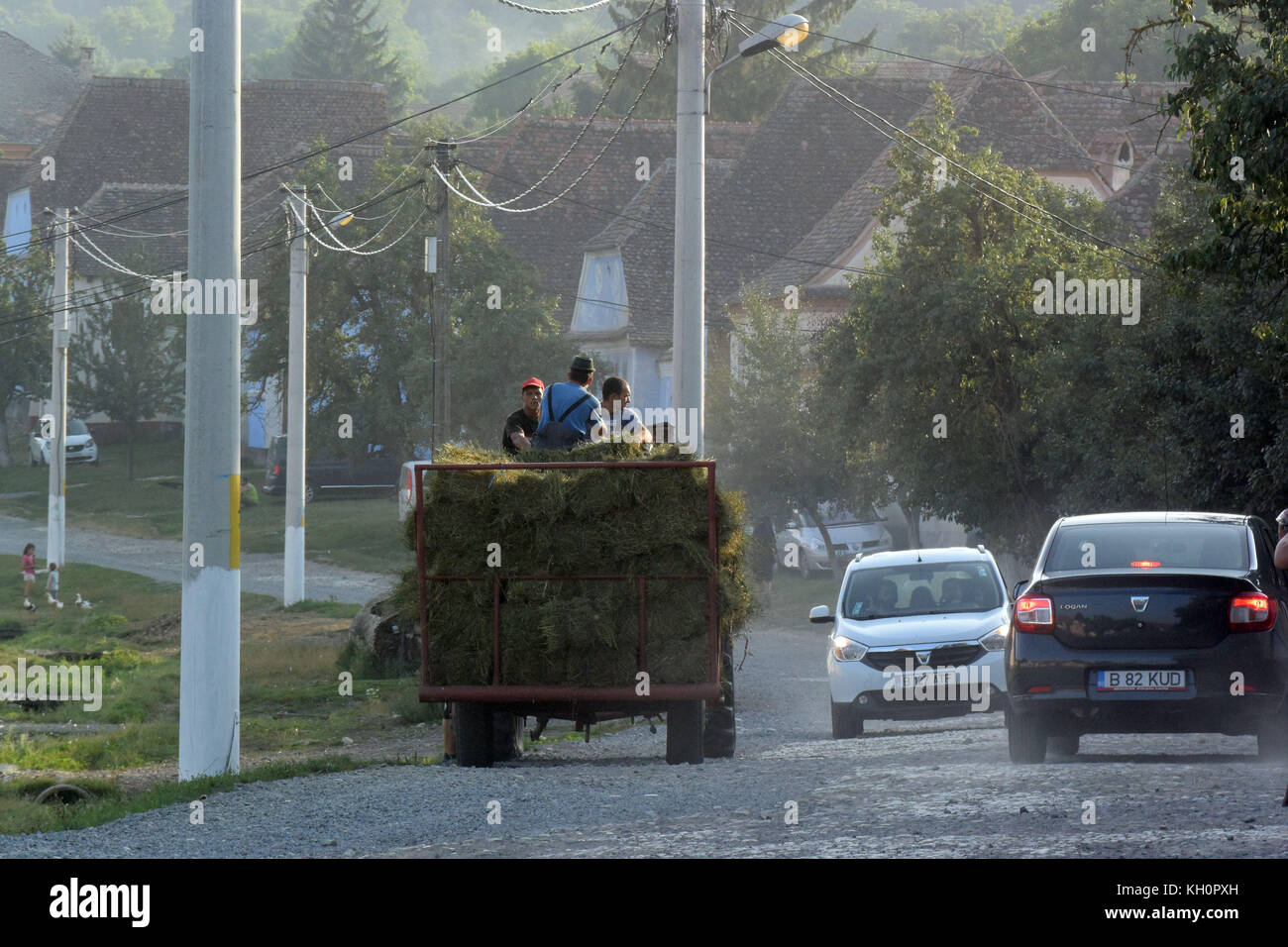 A tractor and two cars passing through the town in Viscri, Transylvania ...