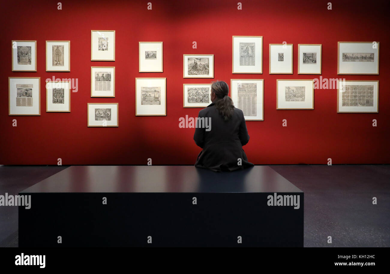 A woman sitting in front of a collection of historical flyers in the ...