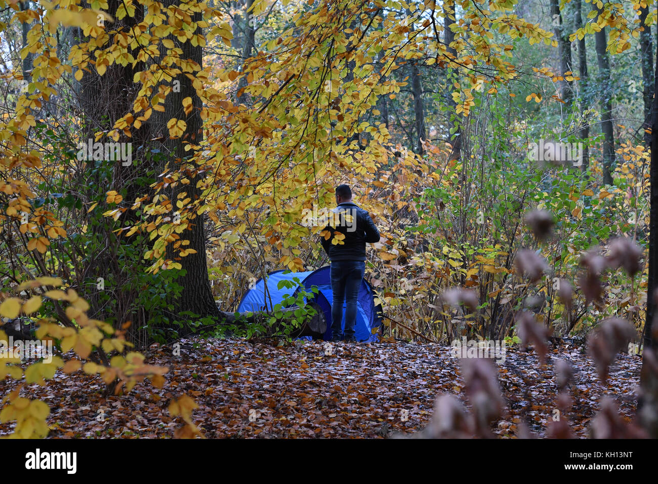 A homeless man standing next to a tent in the Tiergarten park in Berlin ...
