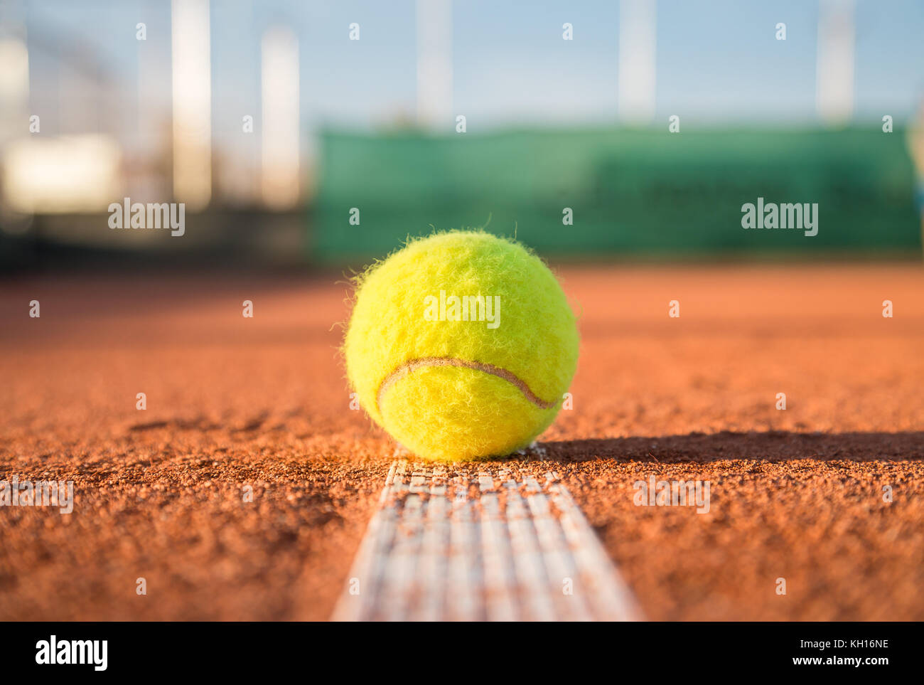 Small tennis ball lying on white line on tennis court on sunny day ...