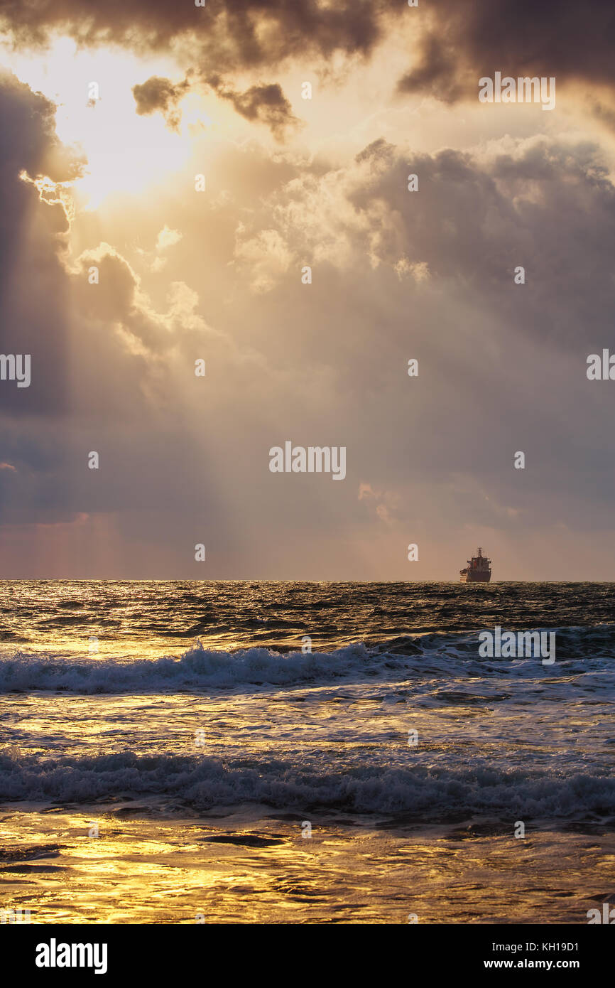 Sun setting at the sea with sailing cargo ship, scenic view Stock Photo ...