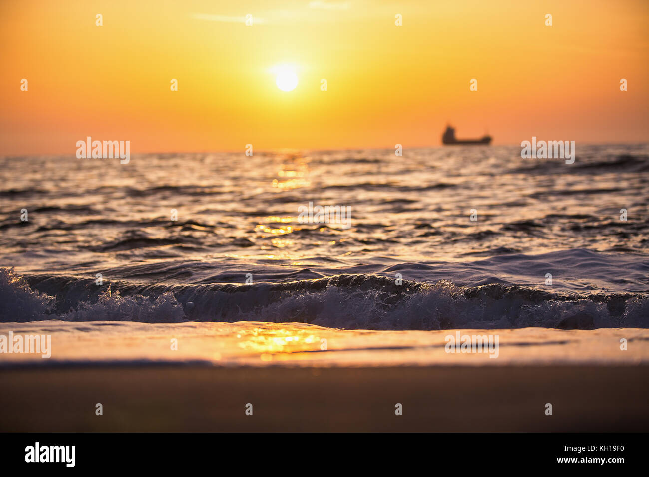 Sun setting at the sea with sailing cargo ship, scenic view Stock Photo ...