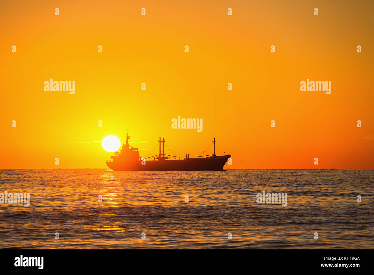 Sun setting at the sea with sailing cargo ship, scenic view Stock Photo ...
