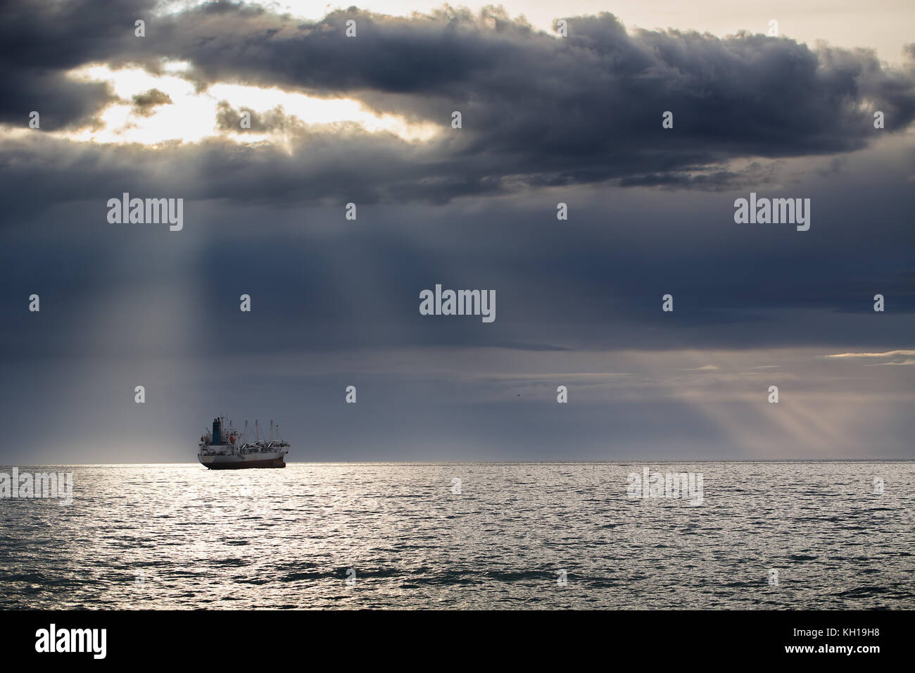 Sun setting at the sea with sailing cargo ship, scenic view Stock Photo ...