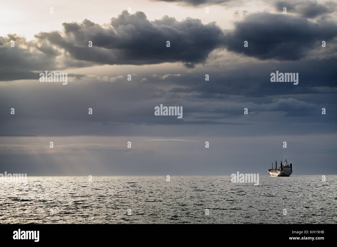 Sun setting at the sea with sailing cargo ship, scenic view Stock Photo ...