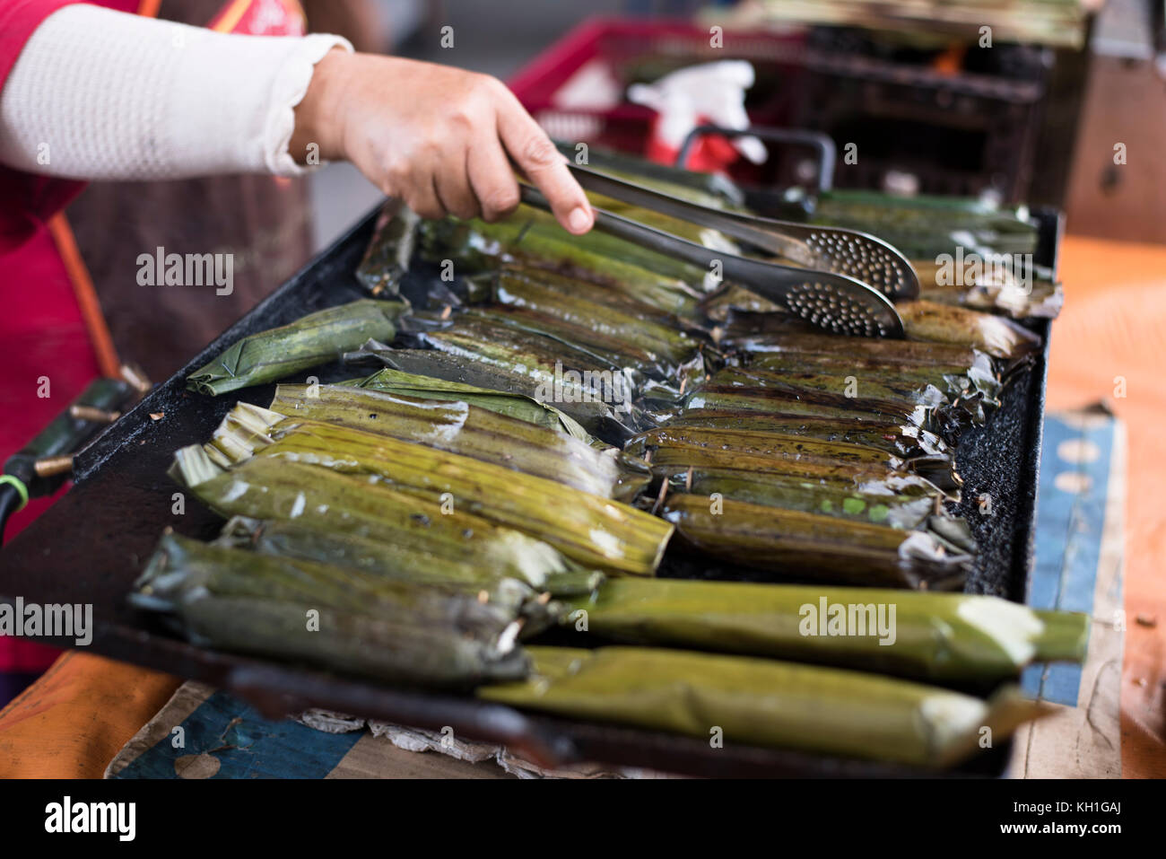 woman holding/cooking glutinous rice with shredded meat wrapped wit ...