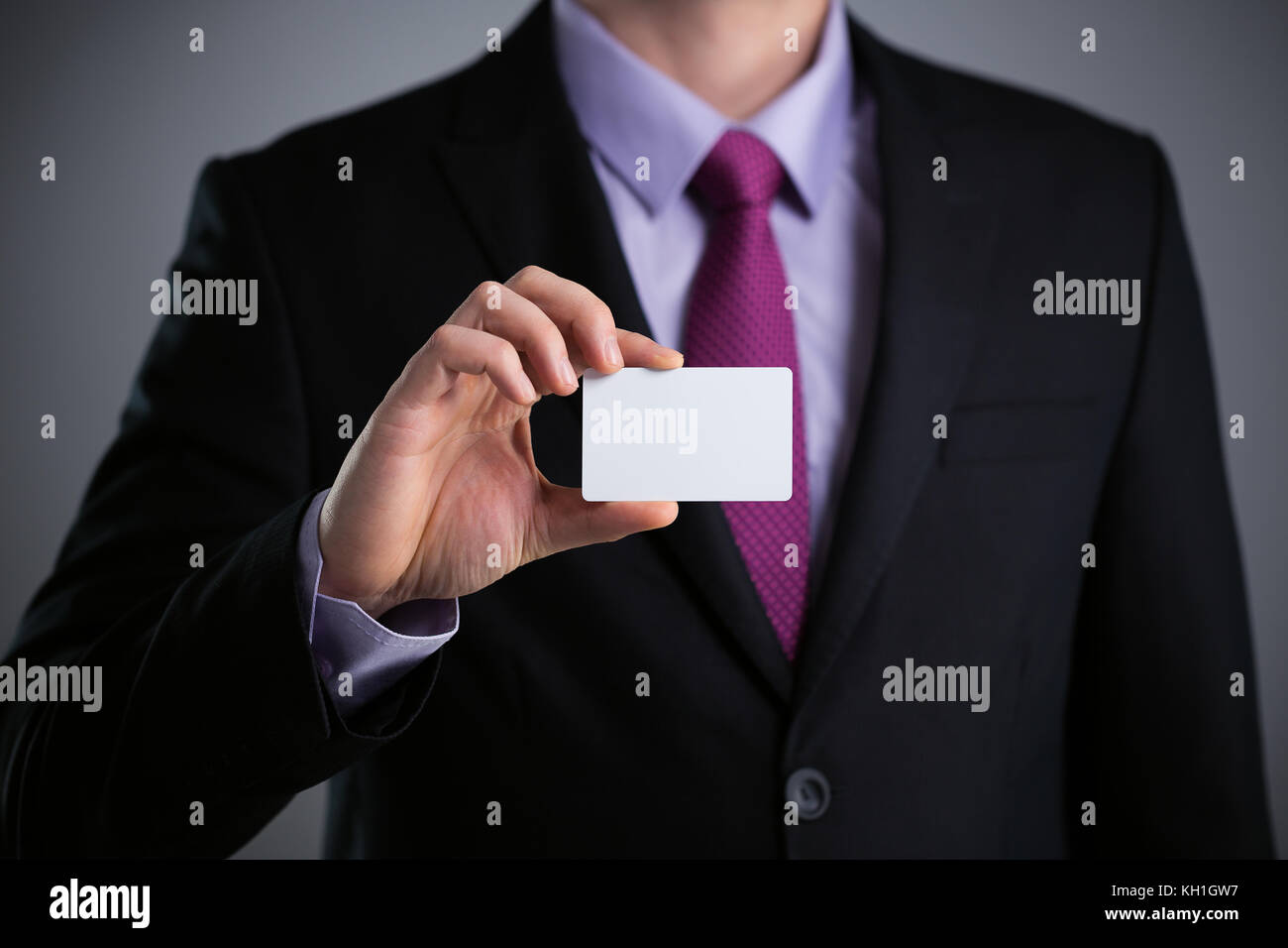 Businessman in elegant suit and with a tie, shows business card with ...