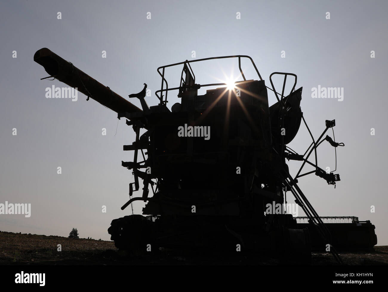 Silhouette of abandoned burnt out combine harvester in field at sunset ...