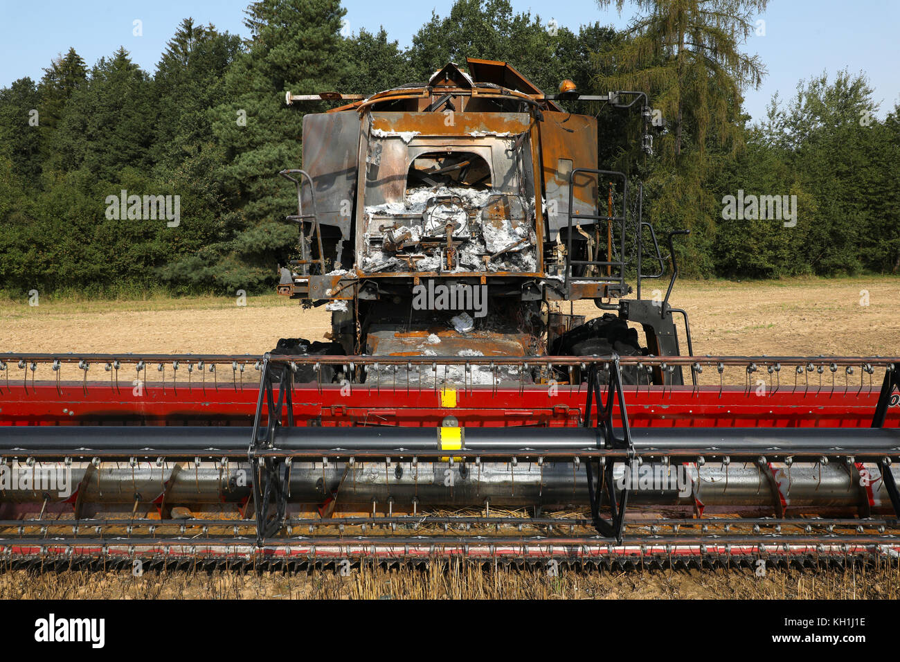 Burnt out combine harvester in field - front view Stock Photo - Alamy