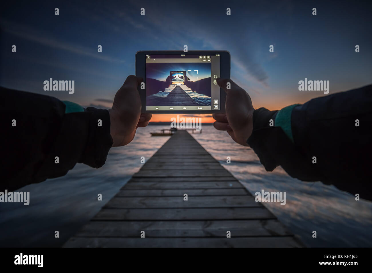 Close-up shot of working tablet on sunset and sea background Stock ...
