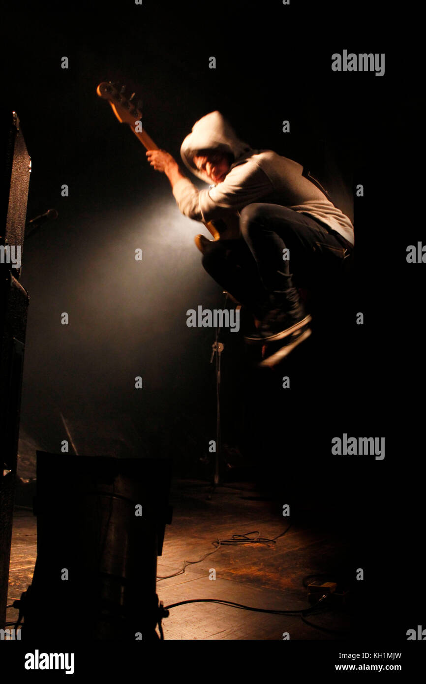 A young musician jumps on stage with his guitar during a live concert ...