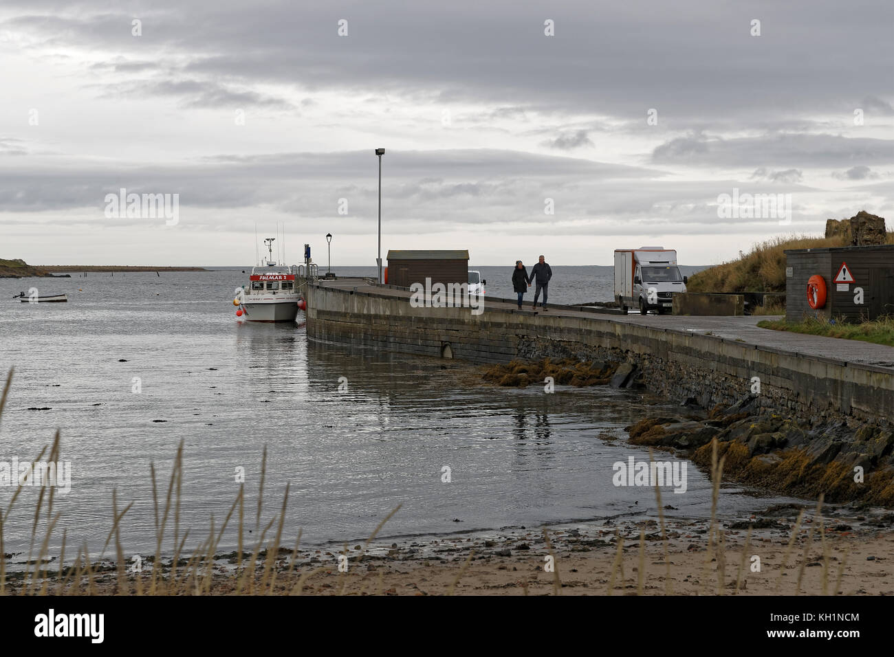 A couple on the quay at Holy Island harbour with fishing vessel Fulmar ...