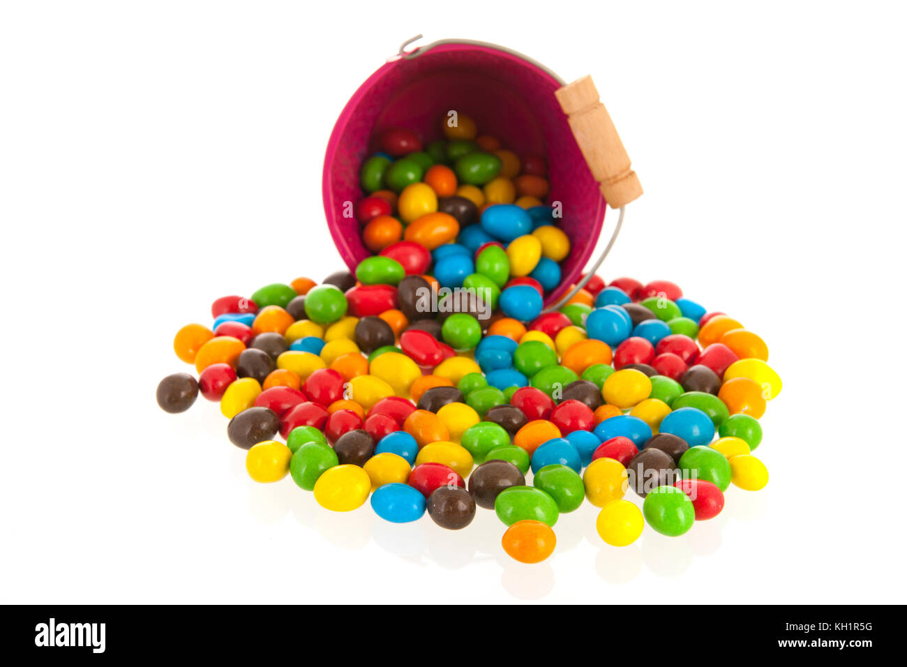 Colorful party candy in pink bucket isolated over white background ...