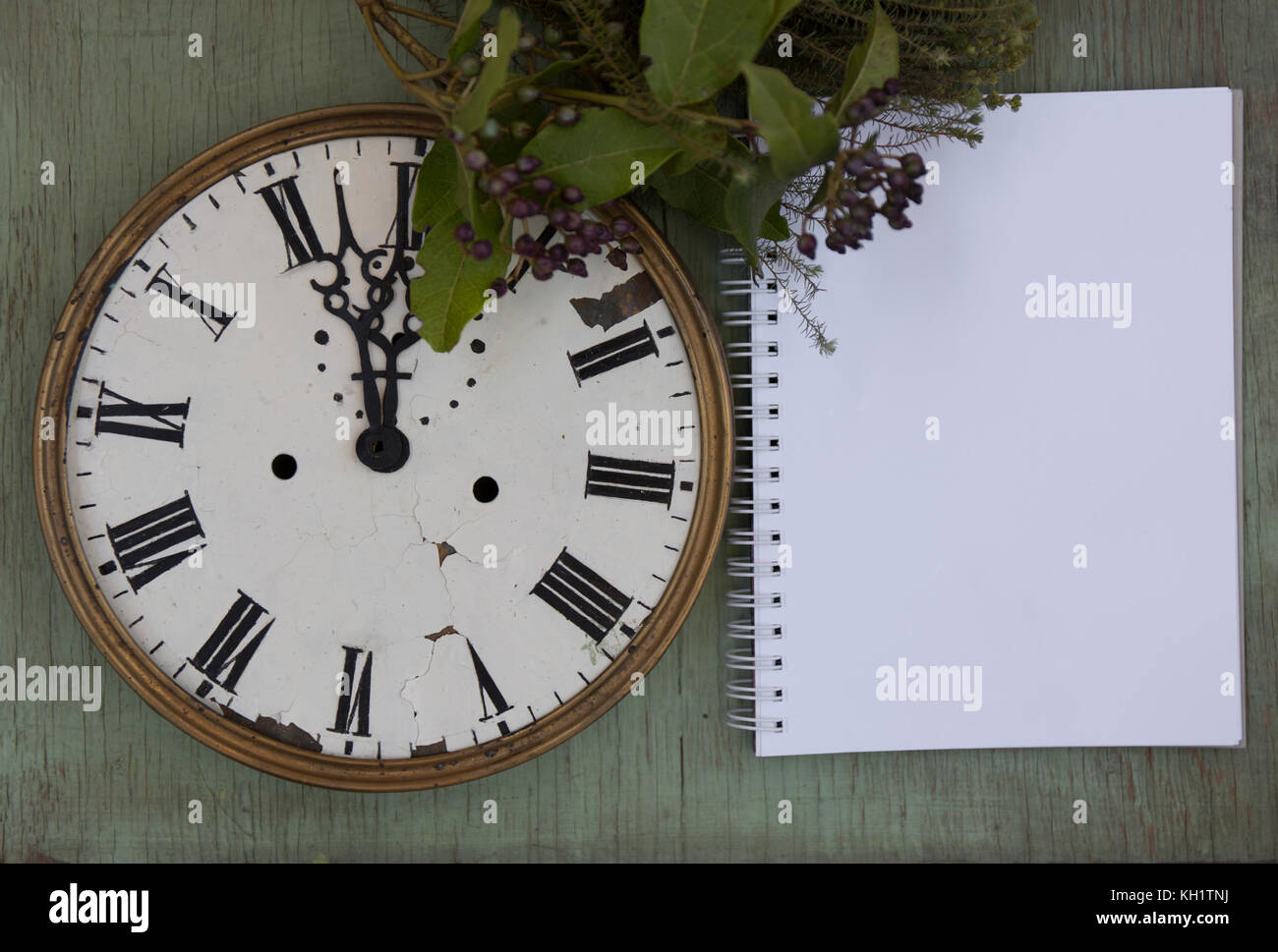 Old clock and blank notepad on the green wood background. New year ...