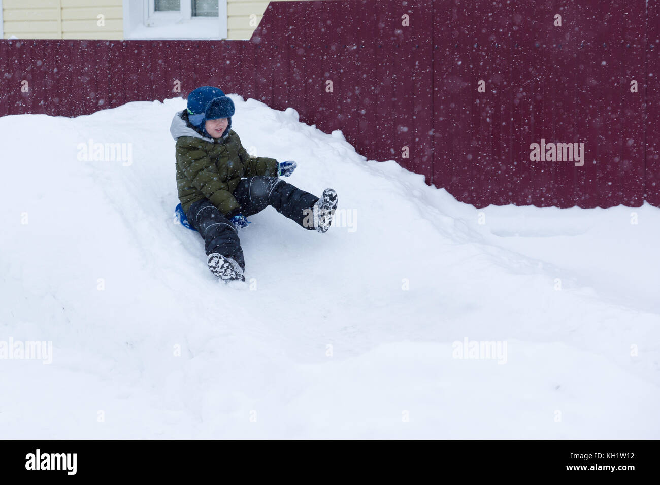 little boy in winter clothes sledding with snow slides Stock Photo - Alamy