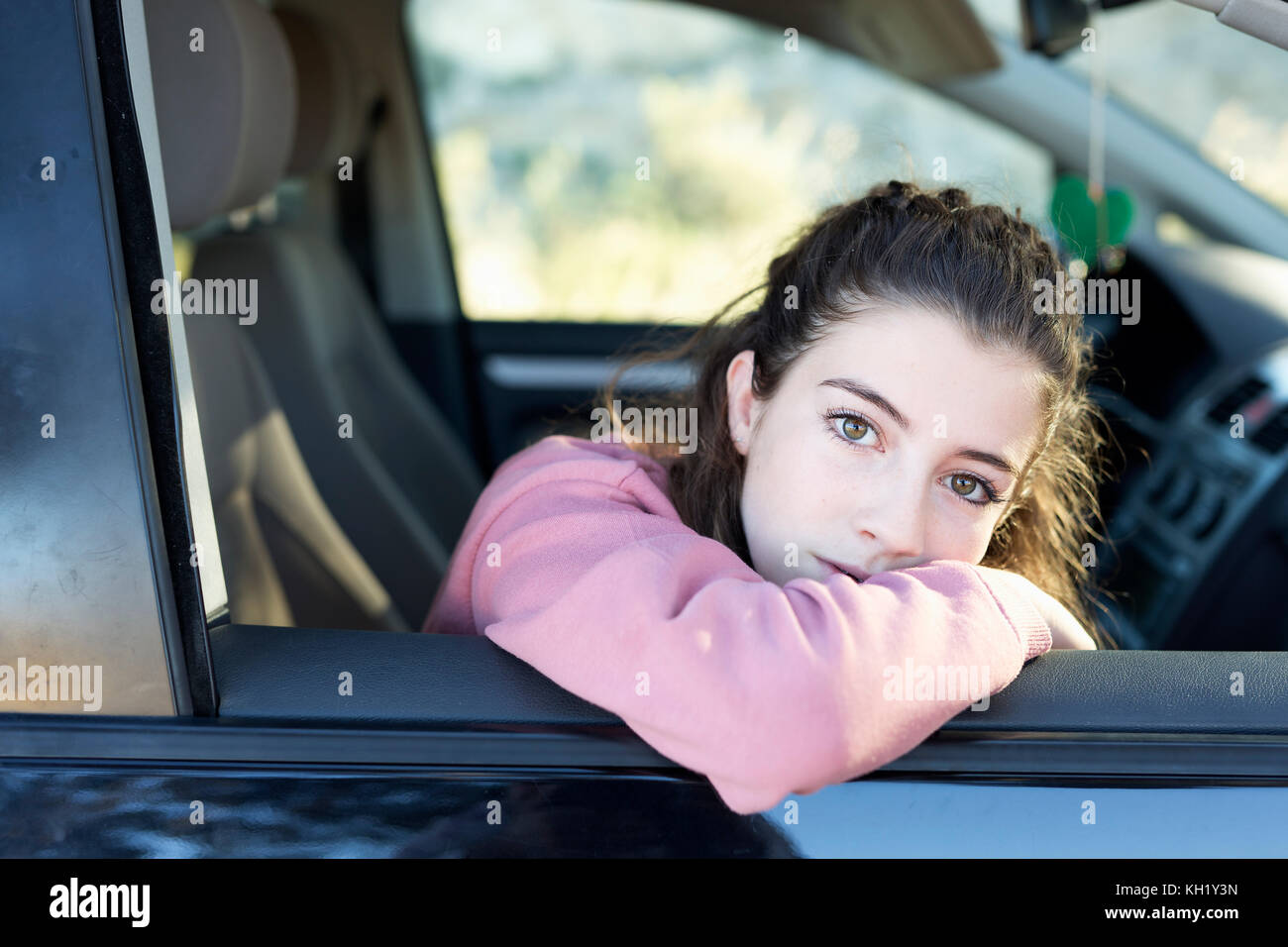 Teenage girl looking out the window of her car. Horizontal shot with ...