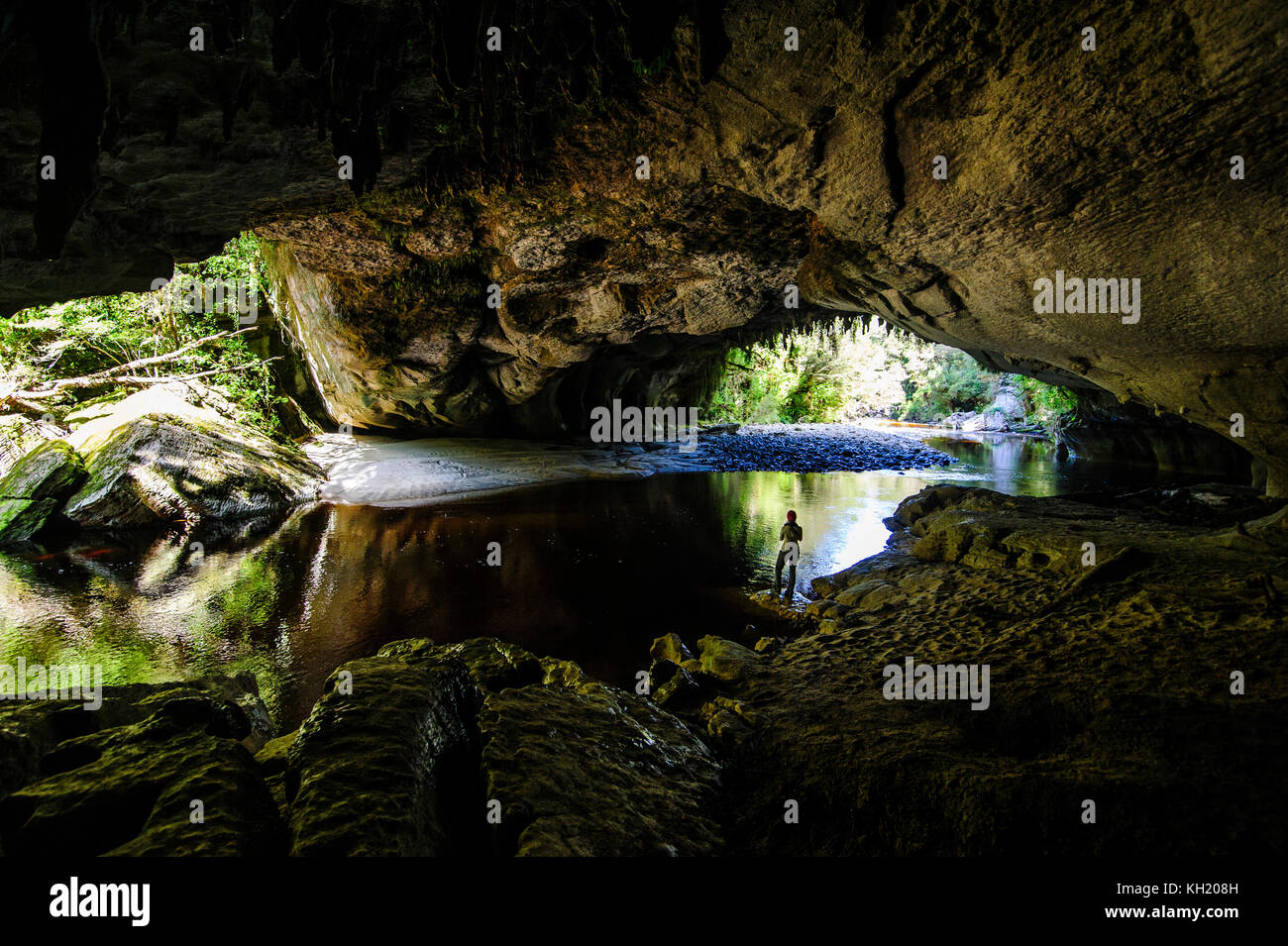 Woman enjoying the stunning Moria gate arch in the Oparara Basin ...