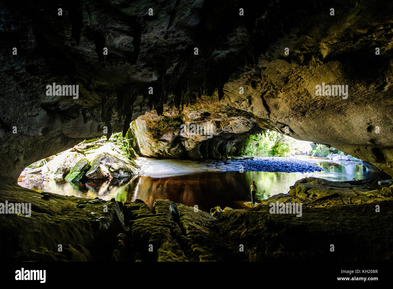 Woman enjoying the stunning Moria gate arch in the Oparara Basin ...