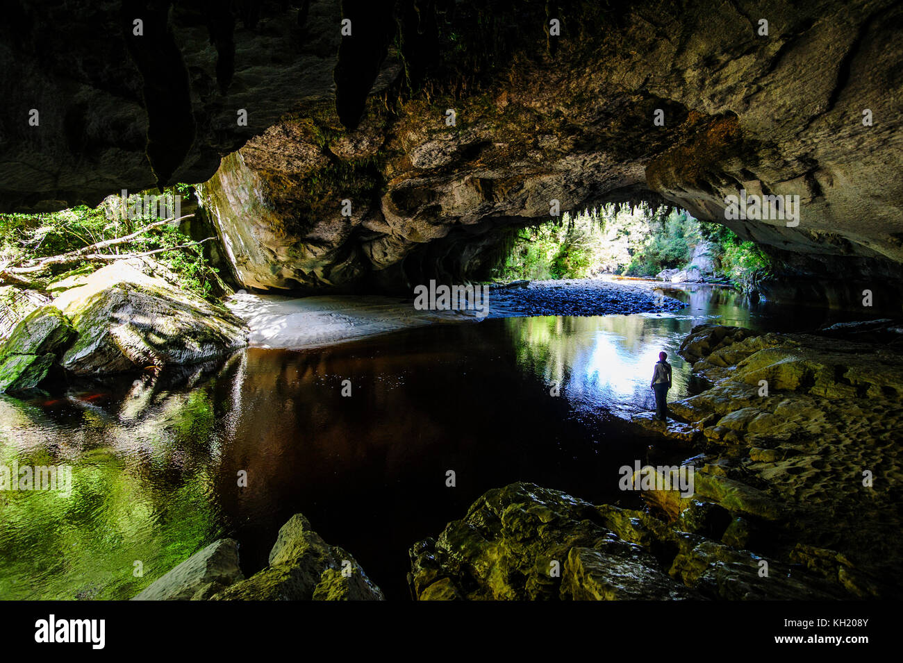 Woman enjoying the stunning Moria gate arch in the Oparara Basin ...