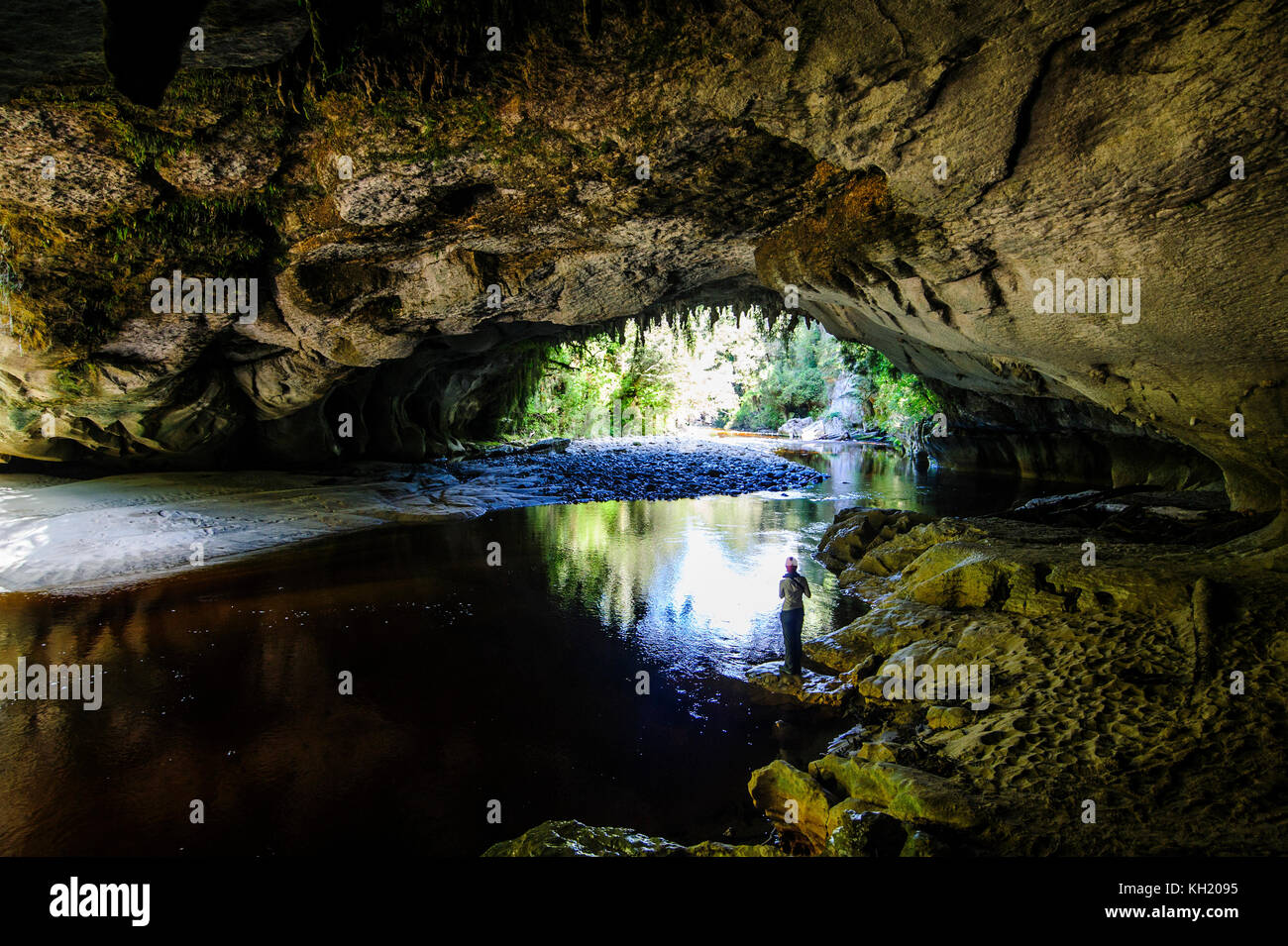 Woman enjoying the stunning Moria gate arch in the Oparara Basin ...