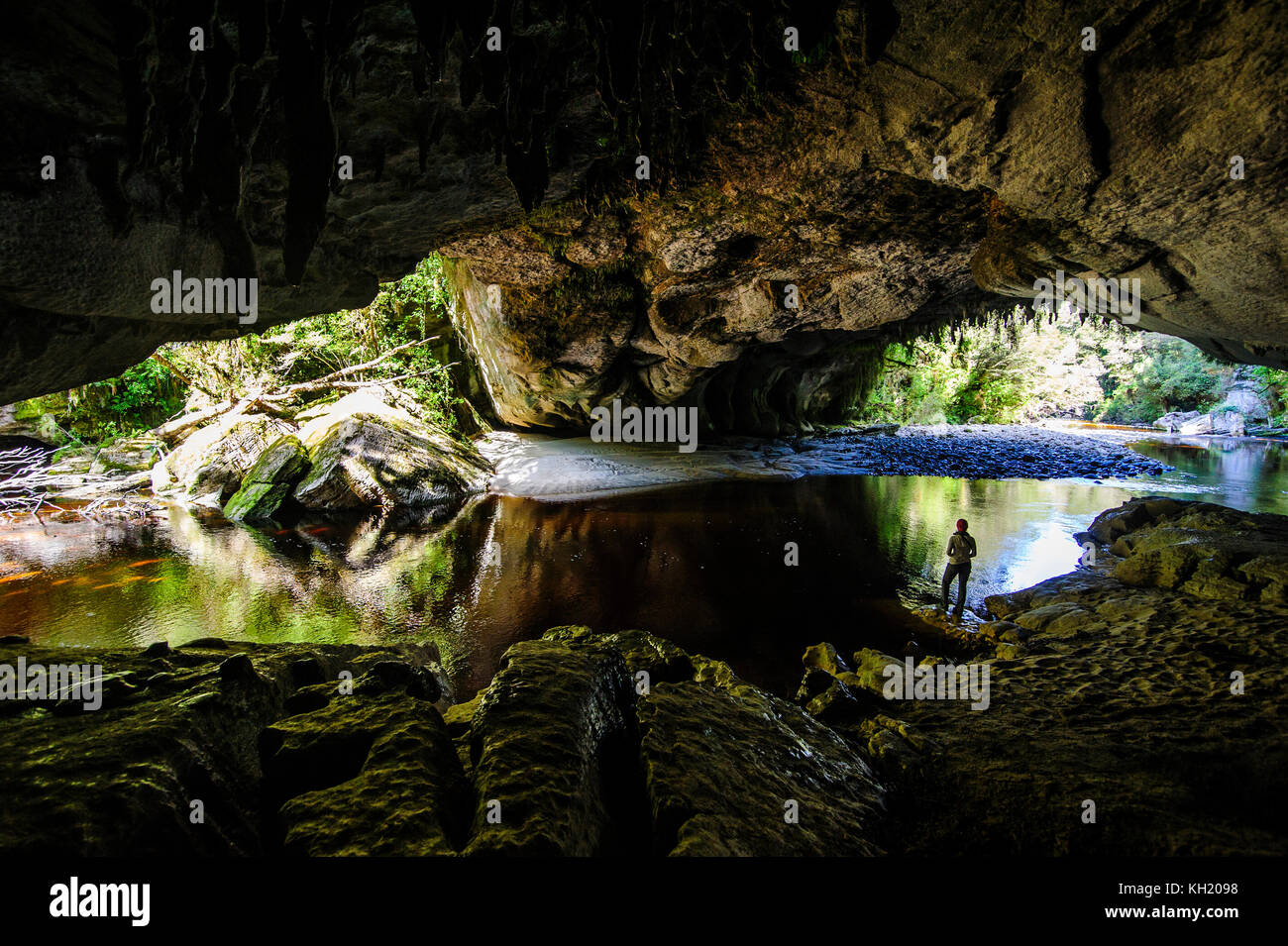 Woman enjoying the stunning Moria gate arch in the Oparara Basin ...