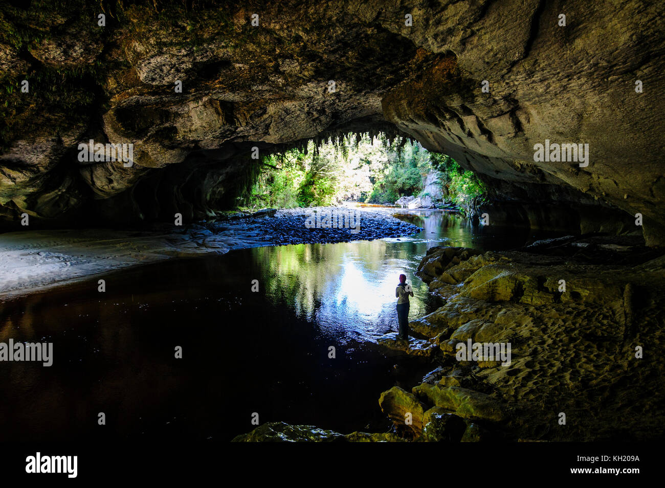 Woman enjoying the stunning Moria gate arch in the Oparara Basin ...