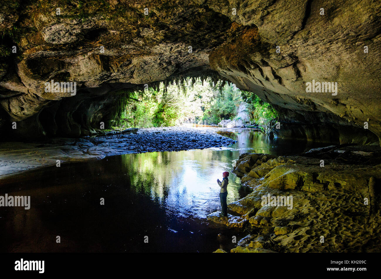 Woman enjoying the stunning Moria gate arch in the Oparara Basin ...