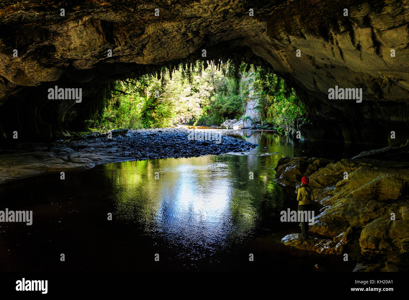 Woman enjoying the stunning Moria gate arch in the Oparara Basin ...