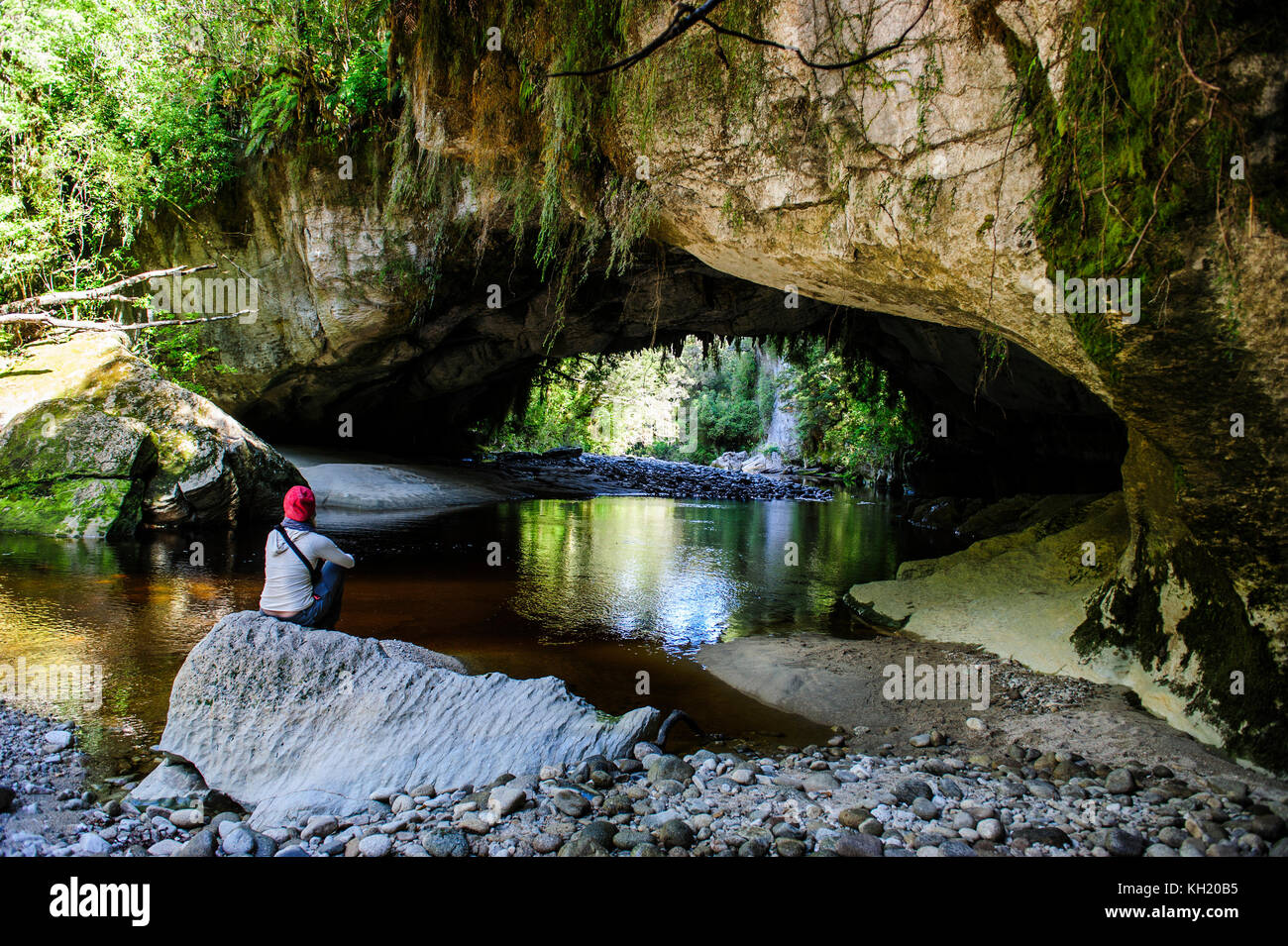 Woman enjoying the stunning Moria gate arch in the Oparara Basin ...