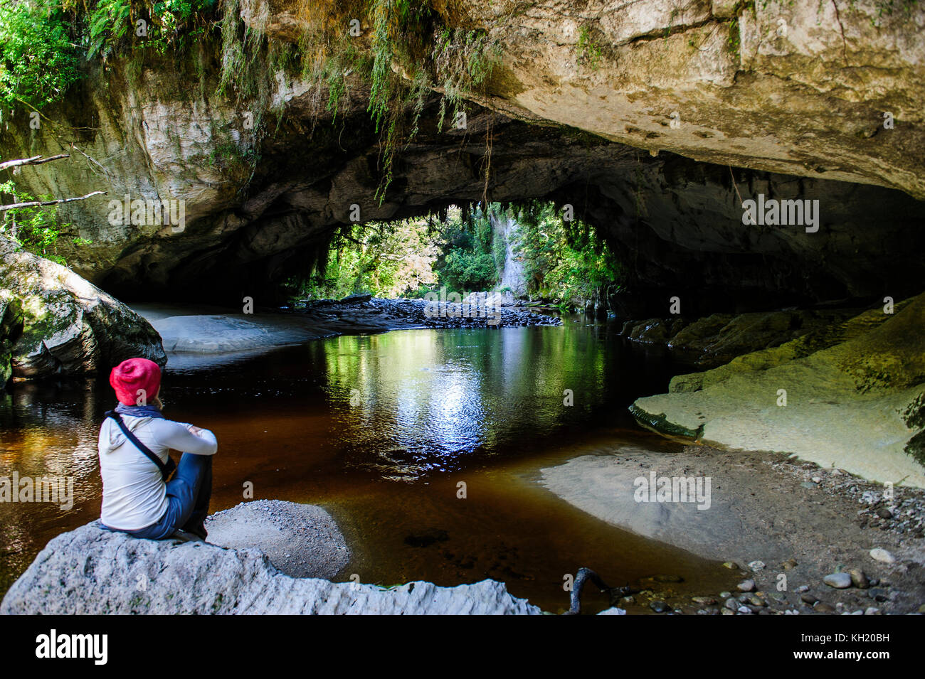 Woman enjoying the stunning Moria gate arch in the Oparara Basin ...