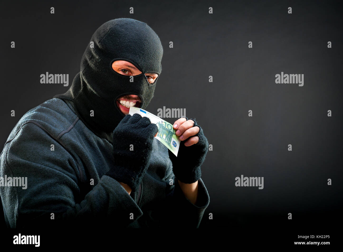 Crime man biting euro Stock Photo - Alamy