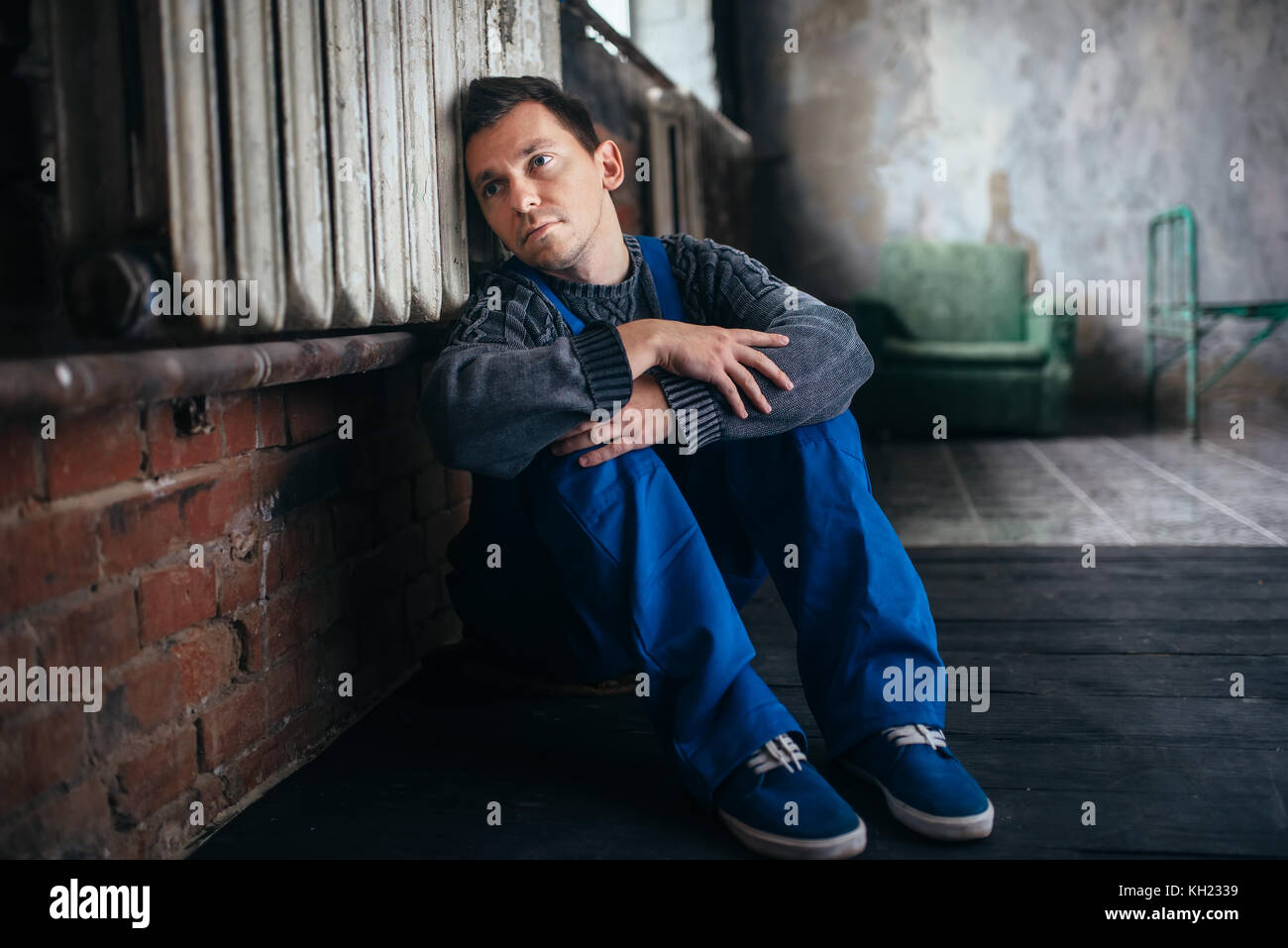 Depressed man sitting on the floor, psycho patient Stock Photo - Alamy