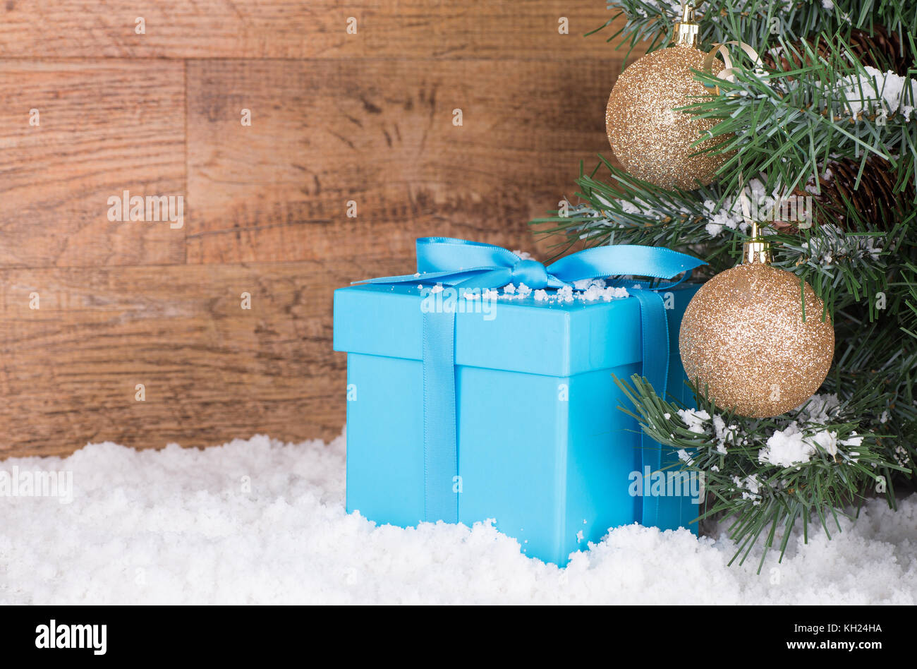 Blue gift box by a Christmas tree with a wood background Stock Photo ...